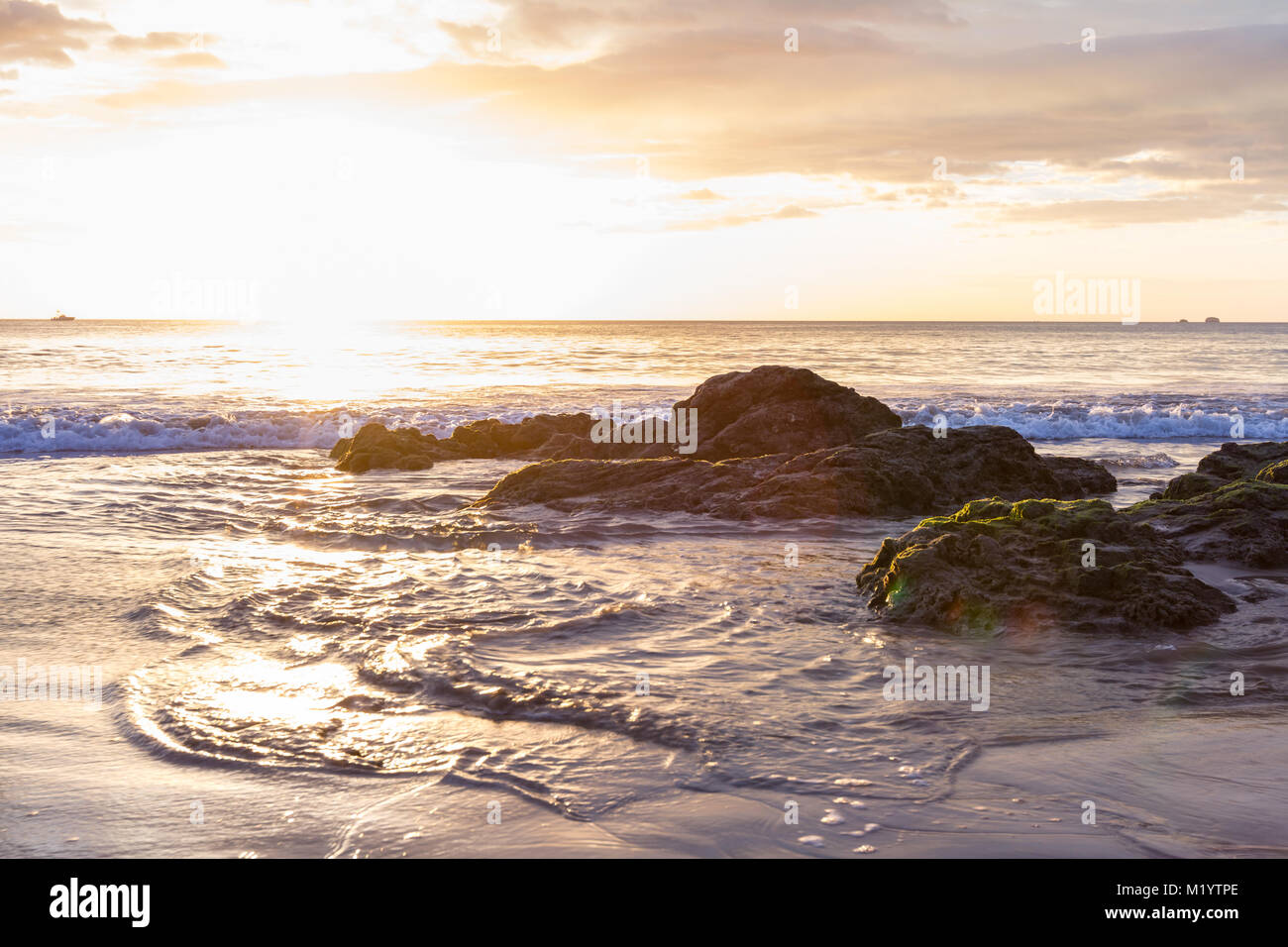 Colorful sunset reflecting on the waves and wet sand with a grouping of ...