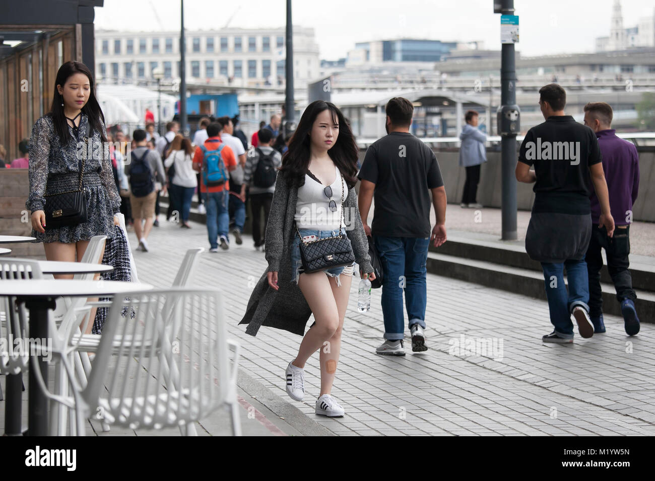 LONDON, ENGLAND - AUGUST 22, 2017 Two girls walking through the crowd ...