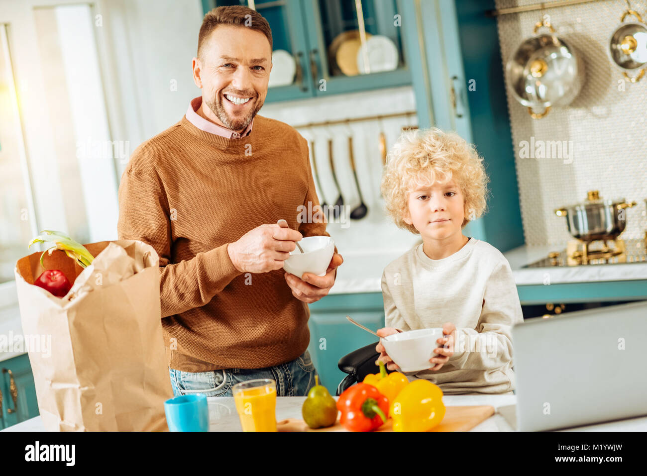 Positive joyful father and son eating breakfast Stock Photo - Alamy