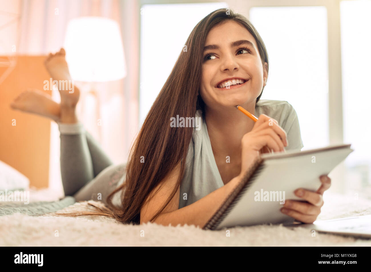 Cheerful teenage girl thinking what to write in notebook Stock Photo ...