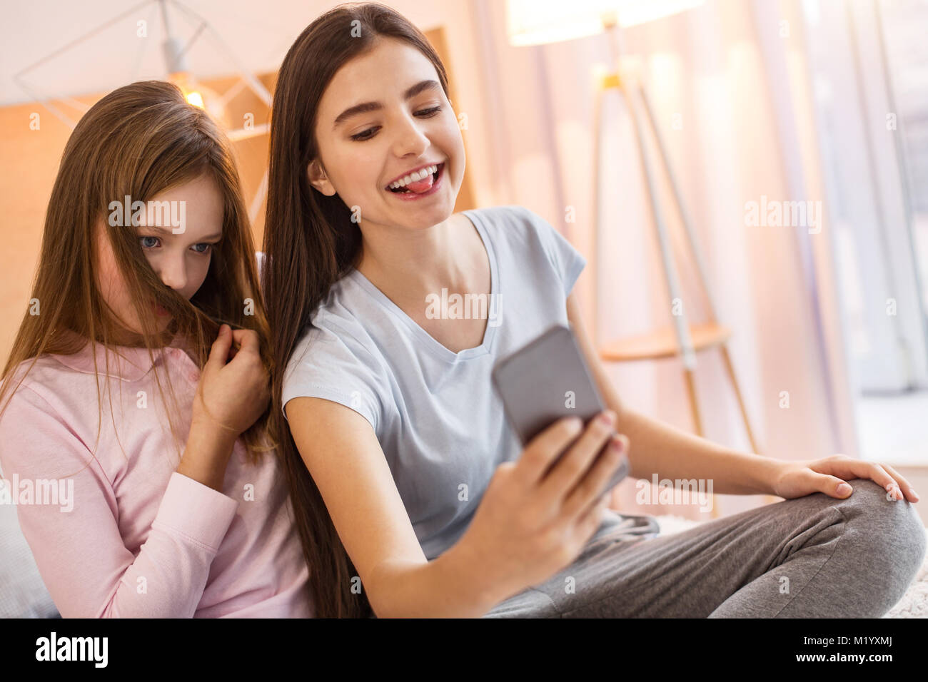 Adorable teenage girls goofing around while taking selfies Stock Photo ...
