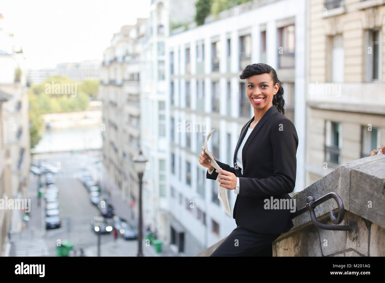 Half Nigerian reporter looking at cam with newspaper on balcony Stock ...