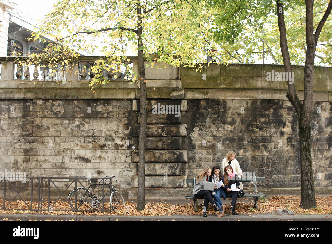 Jocund female students sitting on bench with teacher, laptop, pa Stock ...