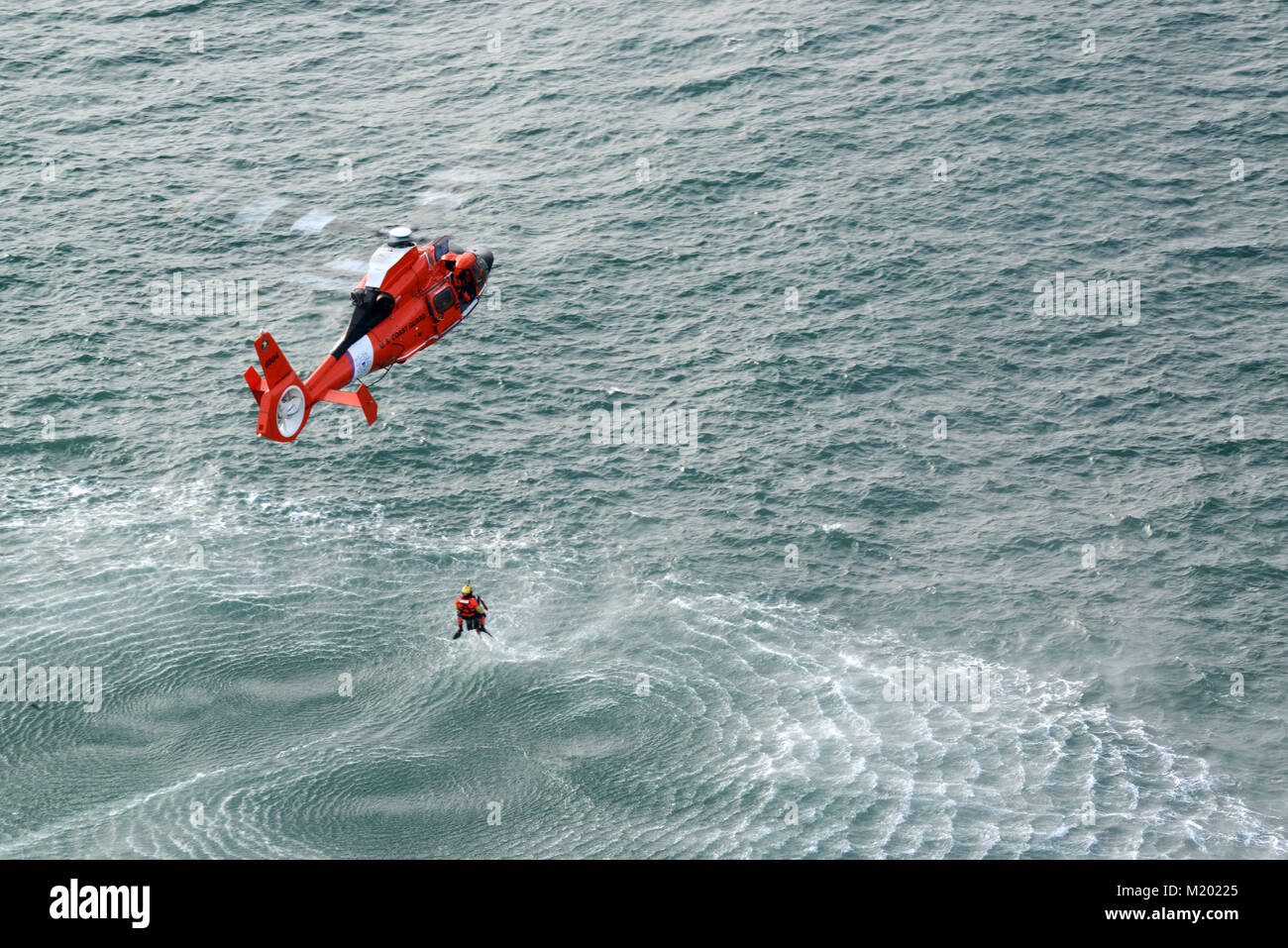 A Coast Guard aviation survival technician, rescue swimmer, is hoisted ...