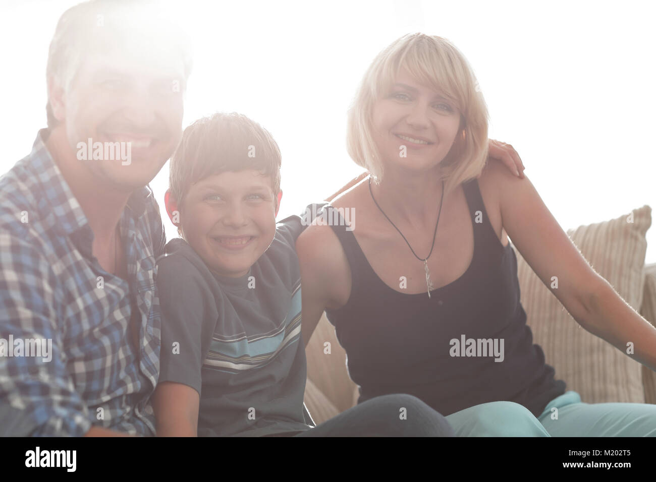 Parents and their son sit huddled in the living room and smiling Stock ...