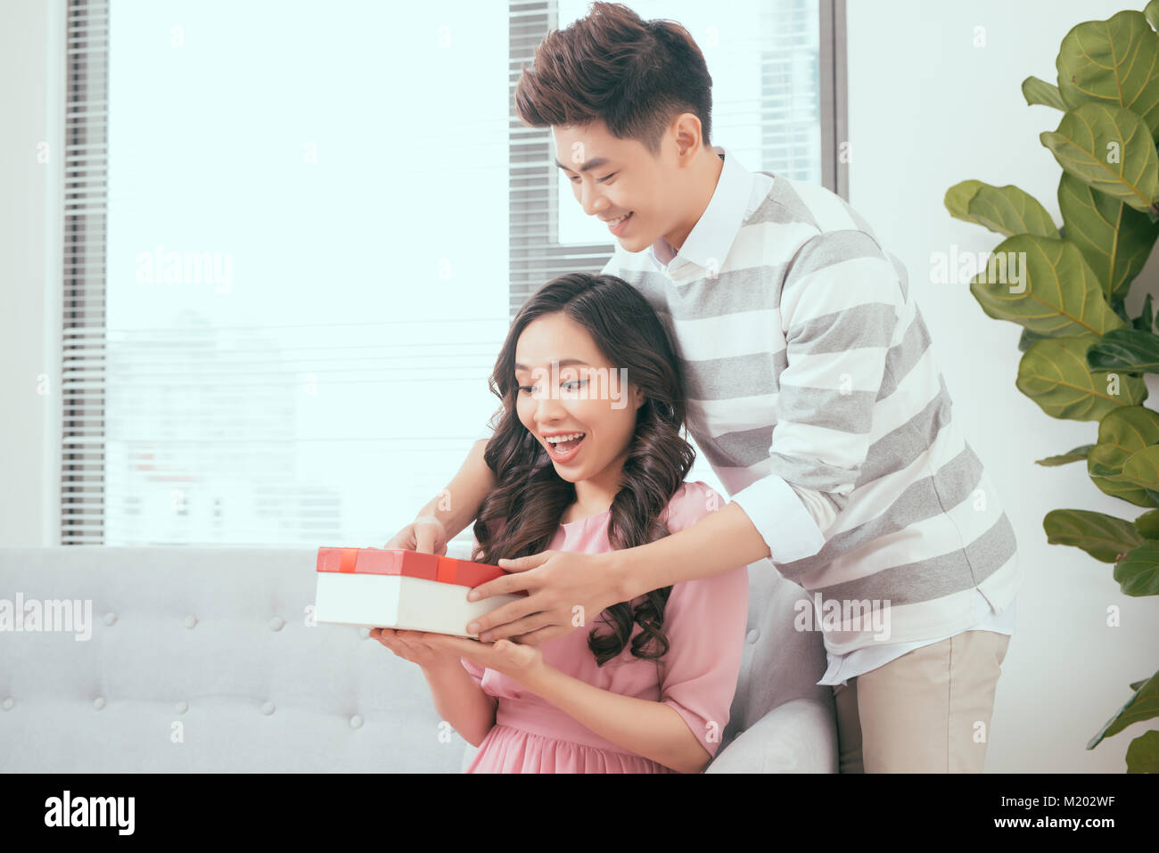 Young couple opening parcel gift box on the couch Stock Photo - Alamy