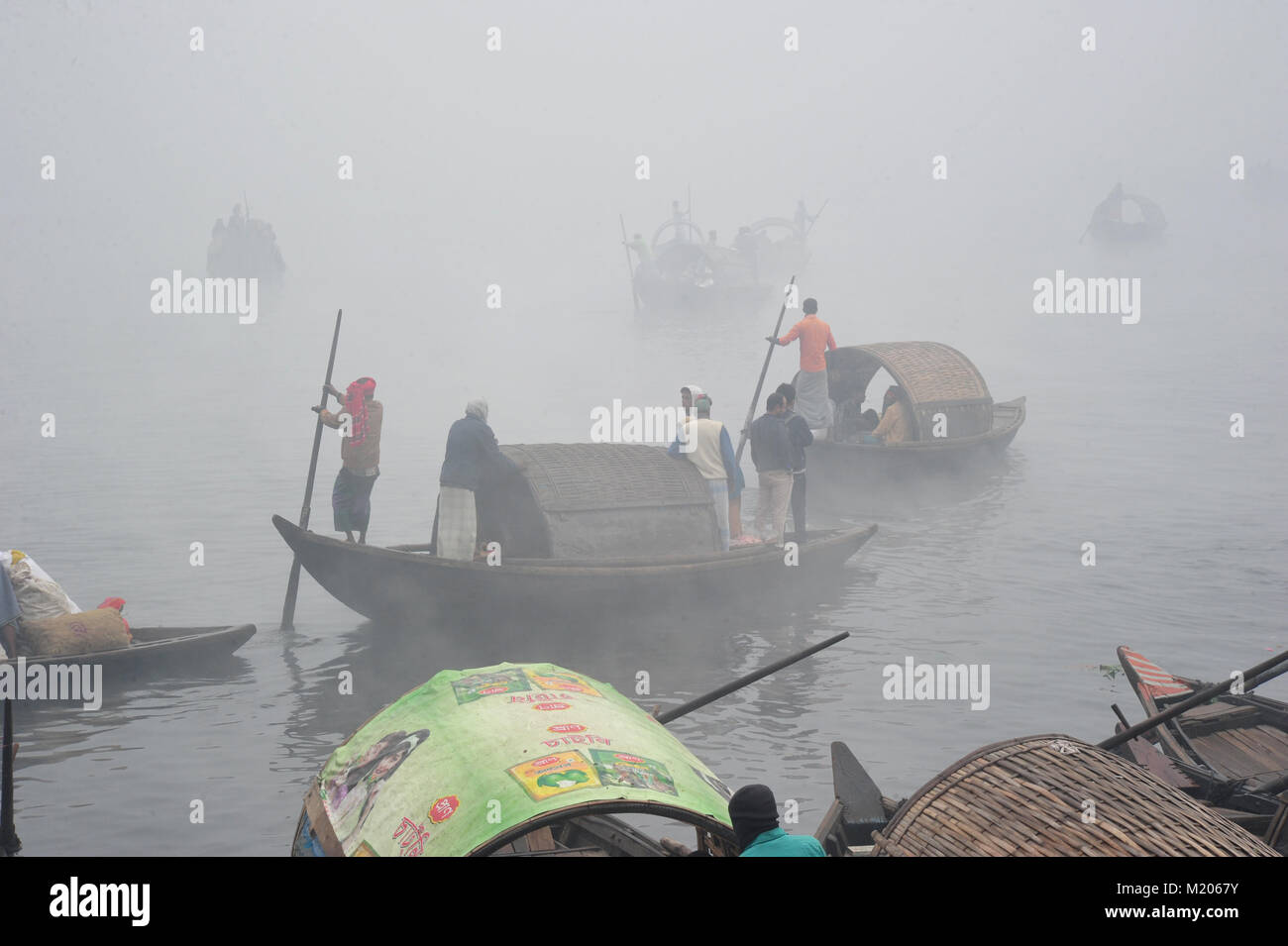Boat men driving their boat with passengers on a cold and foggy winter ...