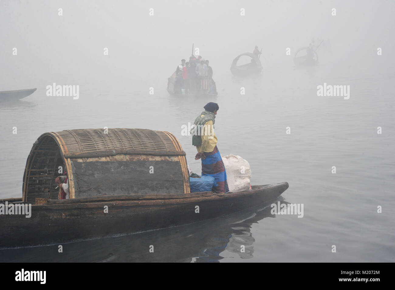 Boat men driving their boat with passengers on a cold and foggy winter ...