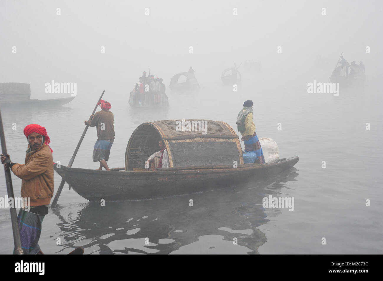 Boat men driving their boat with passengers on a cold and foggy winter ...