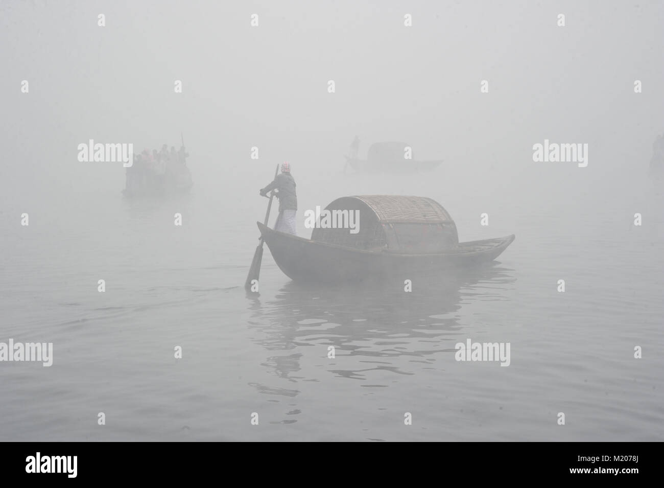 Boat men driving their boat with passengers on a cold and foggy winter ...