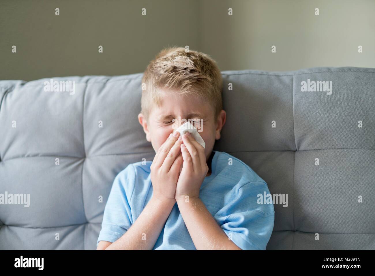 Young boy blowing his nose on a tissue Stock Photo - Alamy