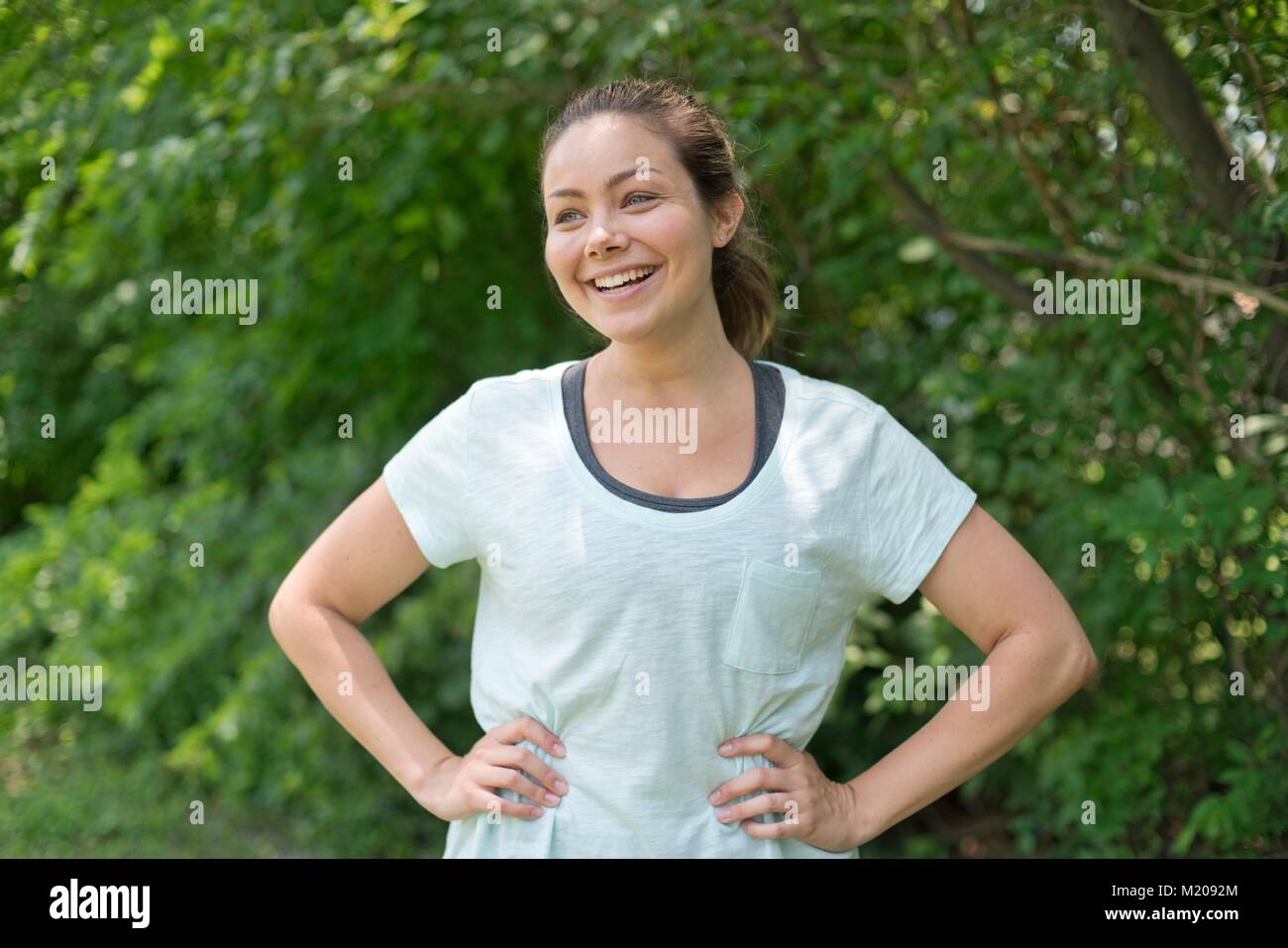 Young woman with hands on hips, smiling Stock Photo - Alamy
