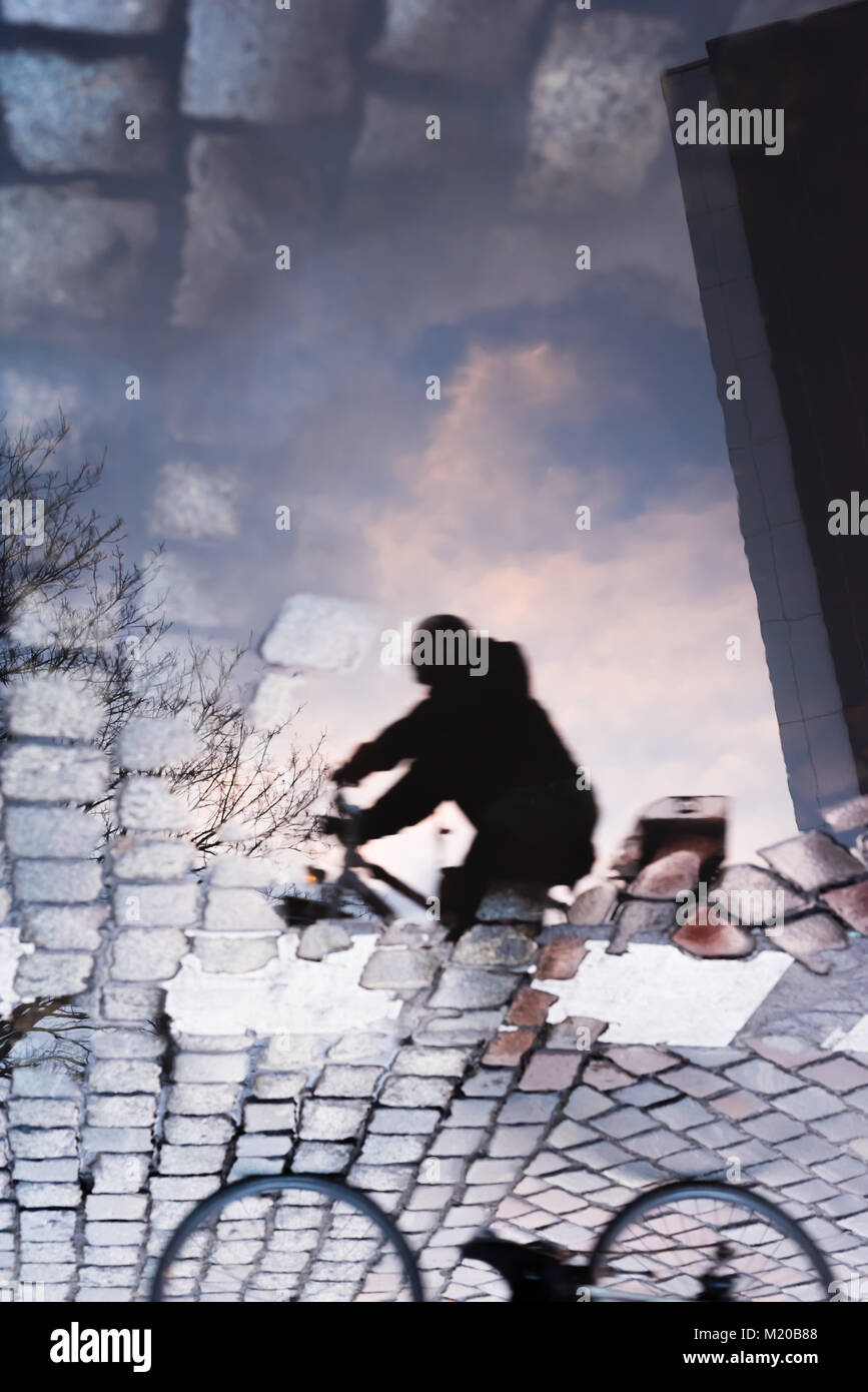 cyclist reflection at a puddle in the city bottom up Stock Photo - Alamy