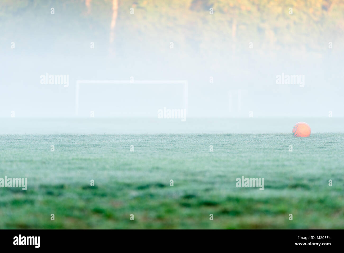 An orange soccer ball off center in front of an out of focus soccer ...