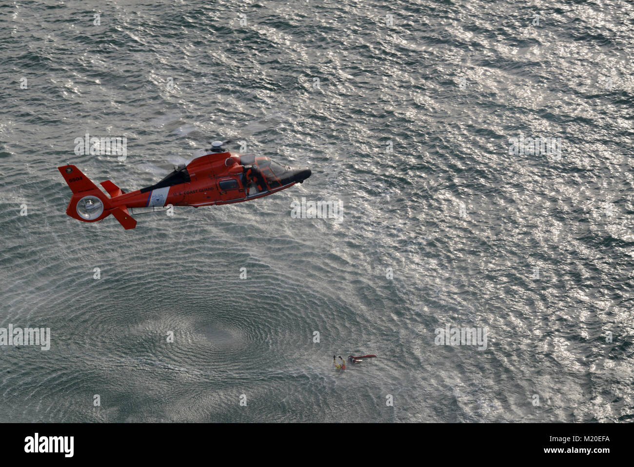 A Coast Guard aviation survival technician, rescue swimmer, signals for ...