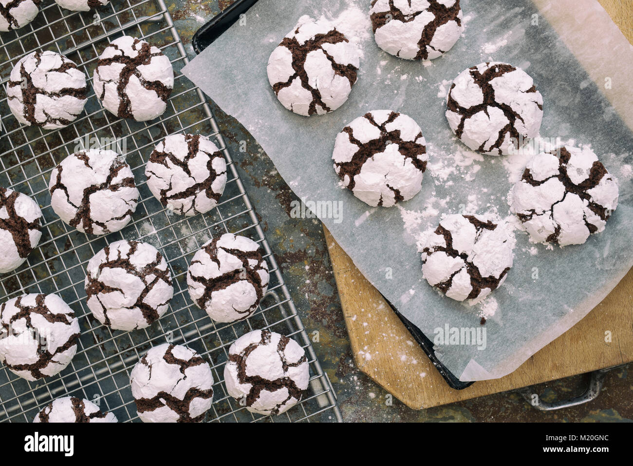 Homemade Chocolate Crinkle Cookies on a baking tray and cooling rack on ...
