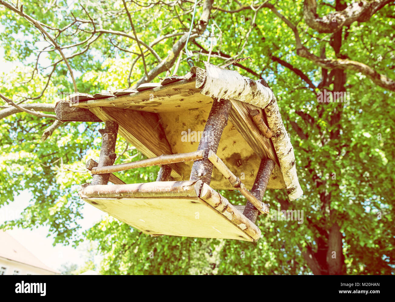 Wooden bird house hanging on the green tree. Seasonal natural scene ...