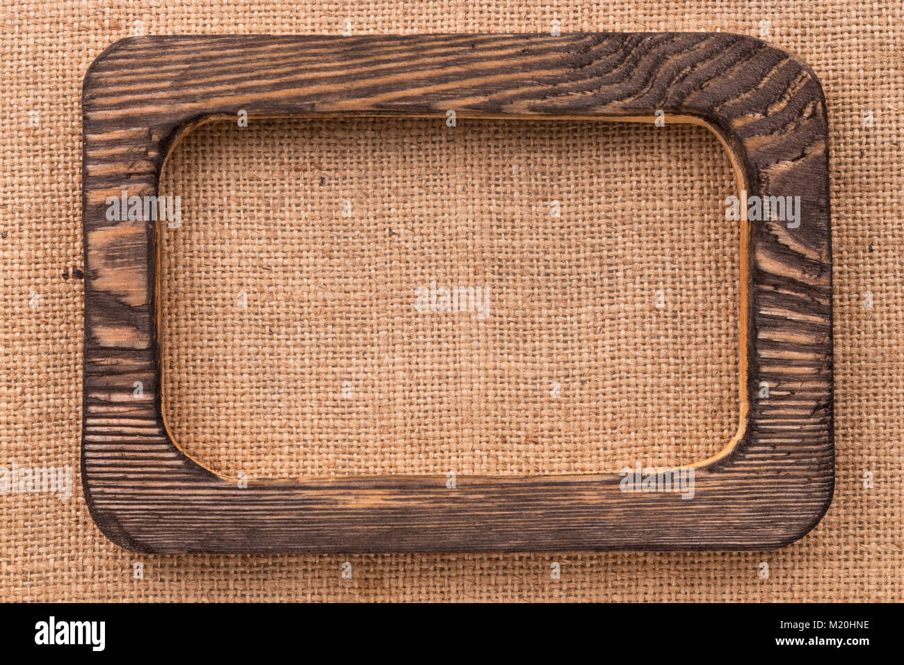 Vintage frame made of dark wood lying on burlap. With space for text ...