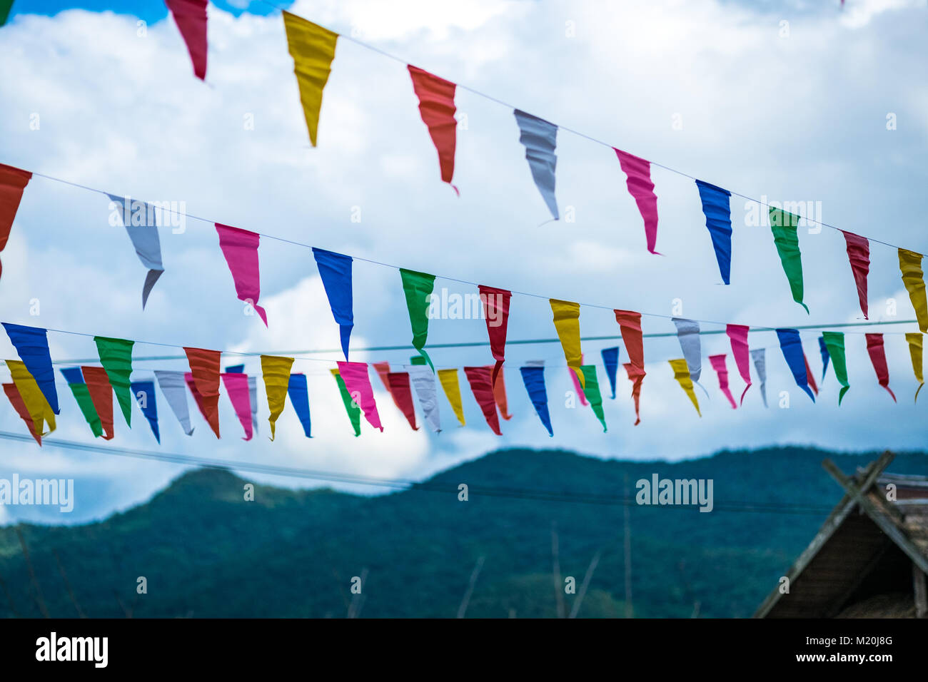 Colorful small flags paper made hanging on the rope with blue sky ...