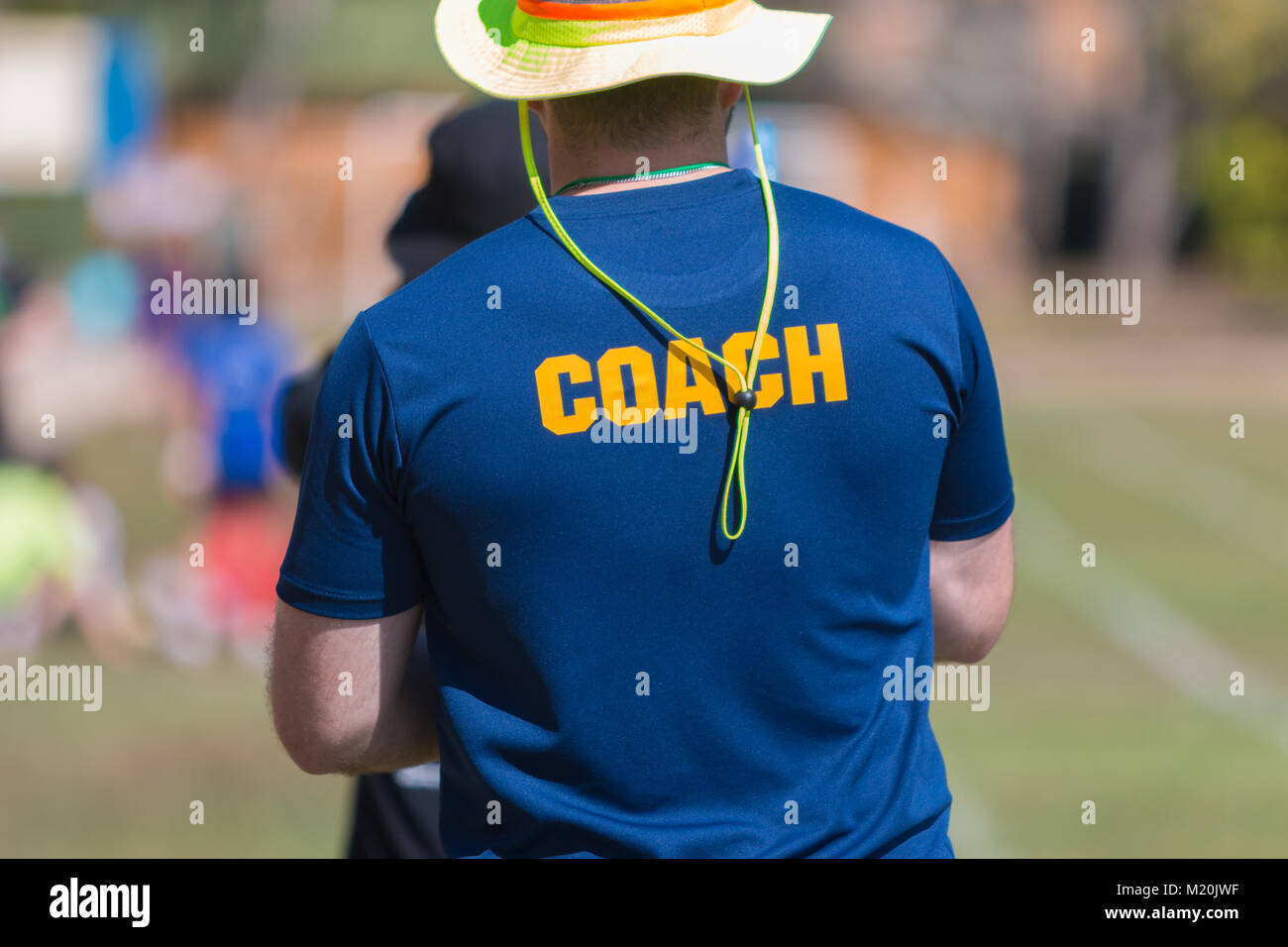back of a coach's blue color shirt with the word Coach in yellow color ...