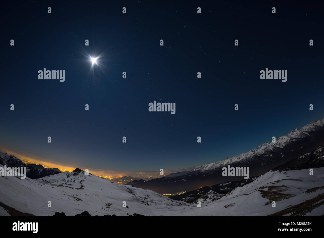 Turin city lights, night view from snow covered Alps by moonlight. Moon ...