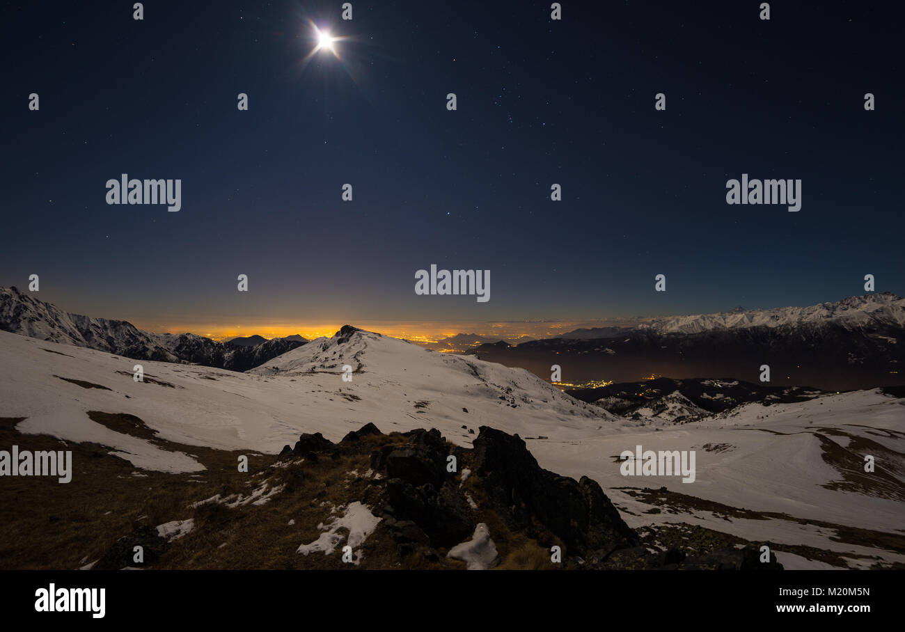 Turin city lights, night view from snow covered Alps by moonlight. Moon ...