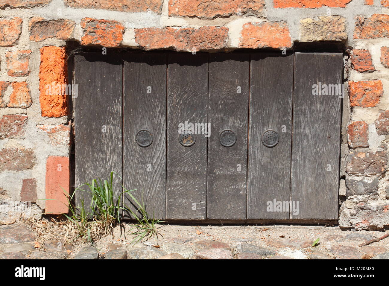 with wooden boards barricaded old cellar window by an old brick stone ...
