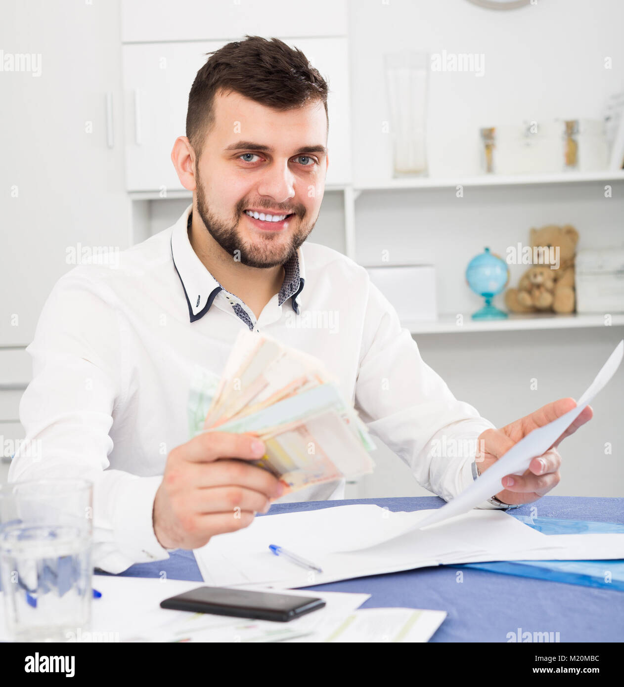 Smiling male worker earning money effectively online at home Stock ...