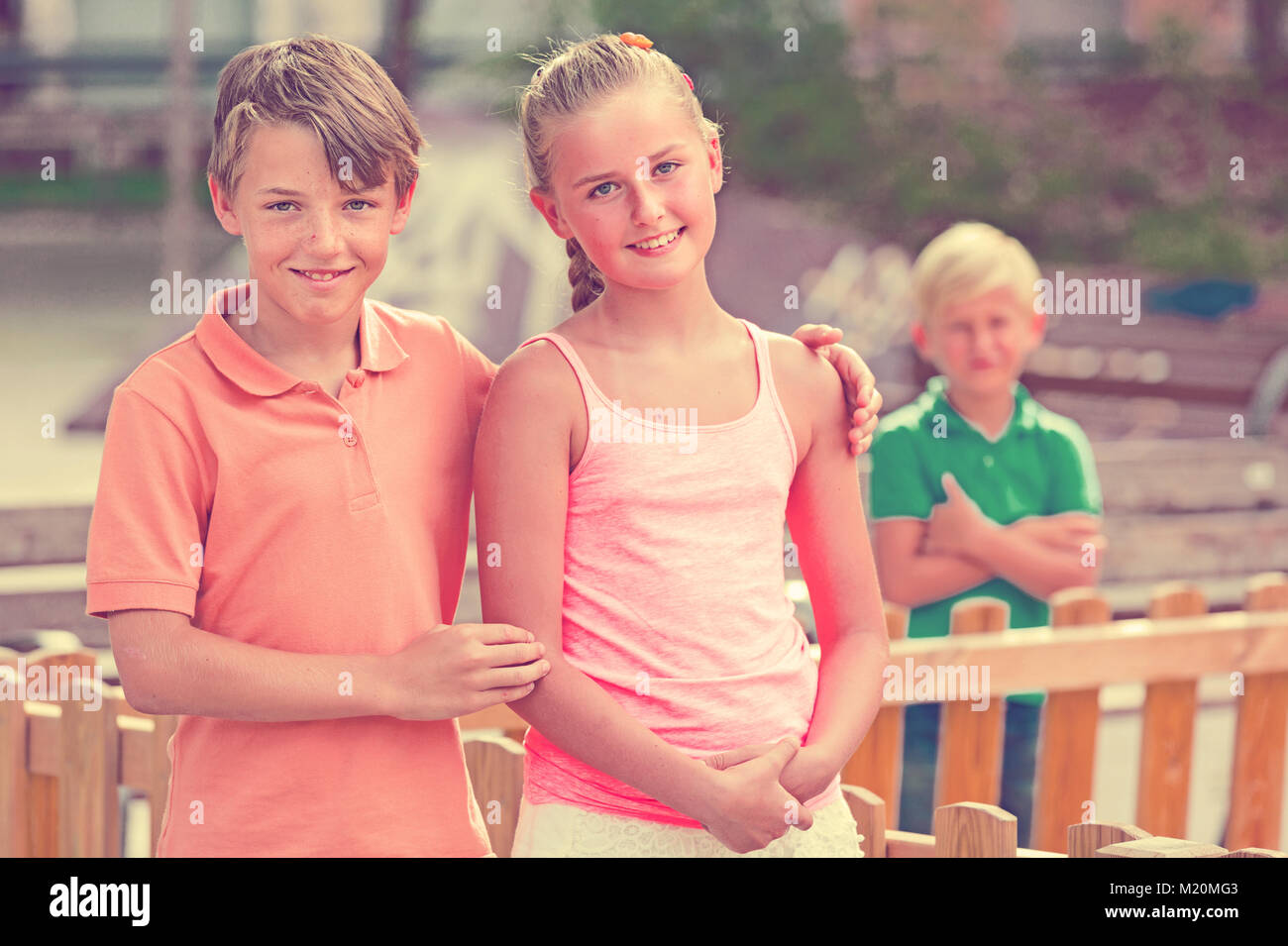 Smiling girl and boy are walking while their friend feeling aggrieved ...