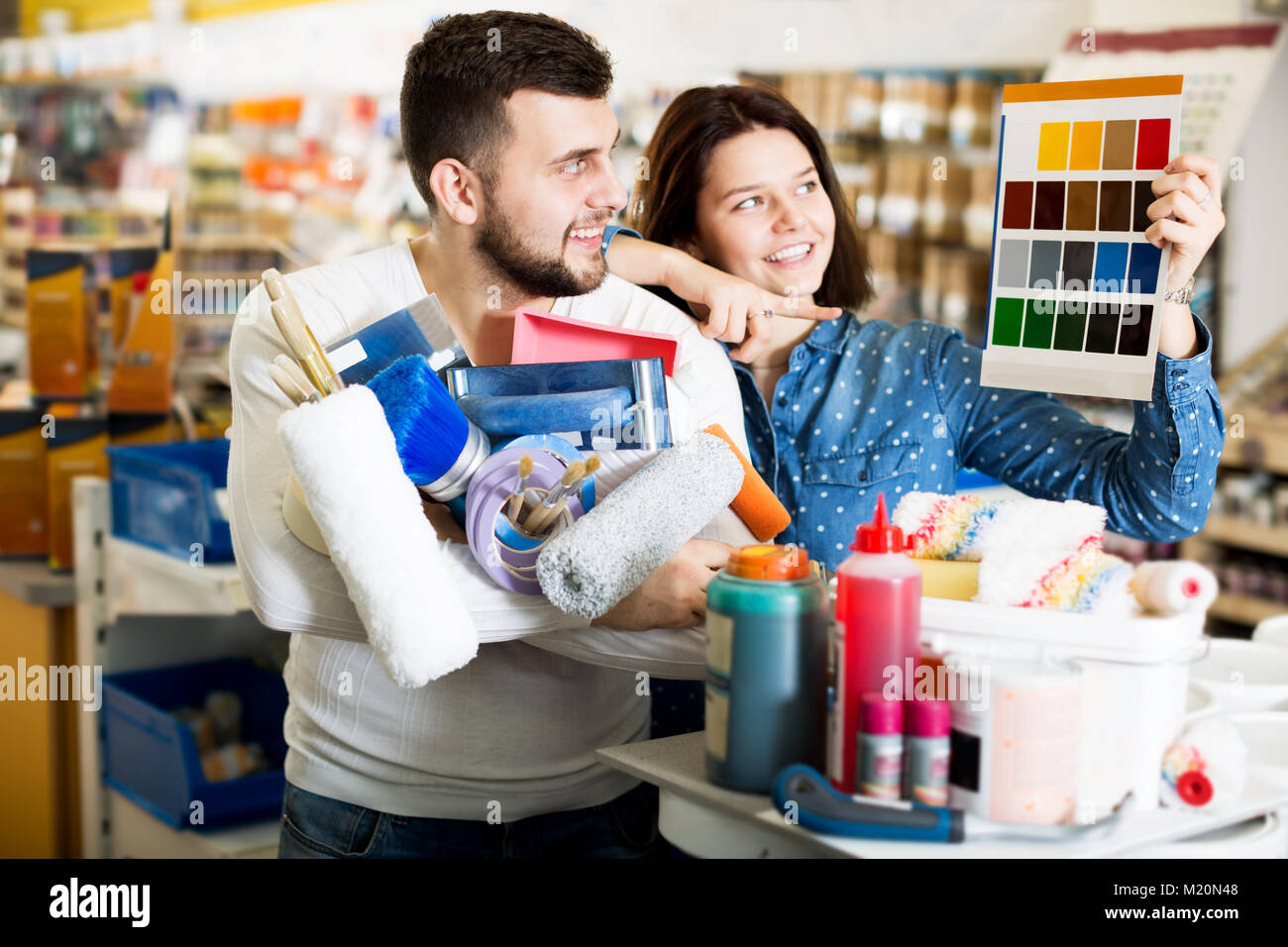 Happy couple examining color scheme variants in paint supplies ...