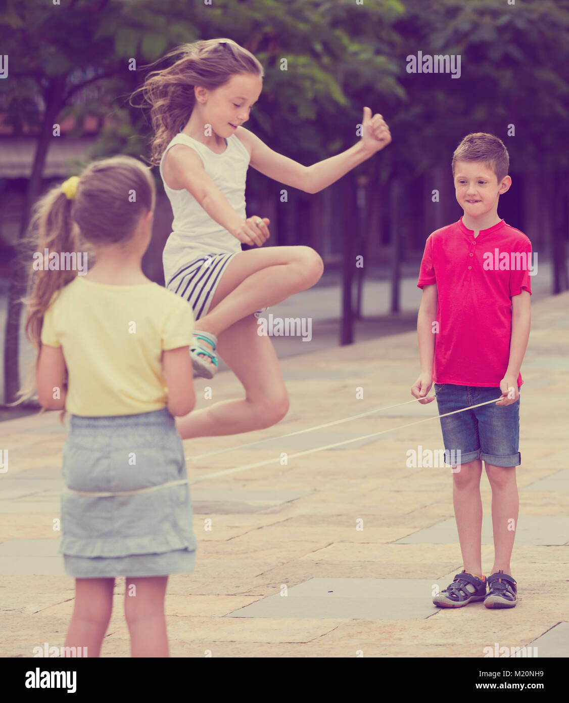 Glad small kids in school age playing together with chinese jumping ...