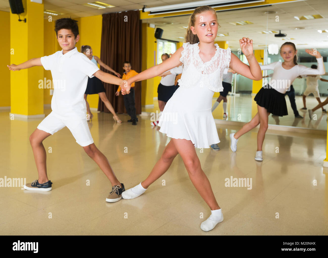Children in dance hall learning new movements, smiling and having fun ...