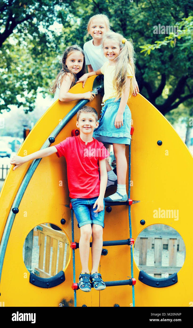 Cheerful kids in school age climbing together on playground's ...