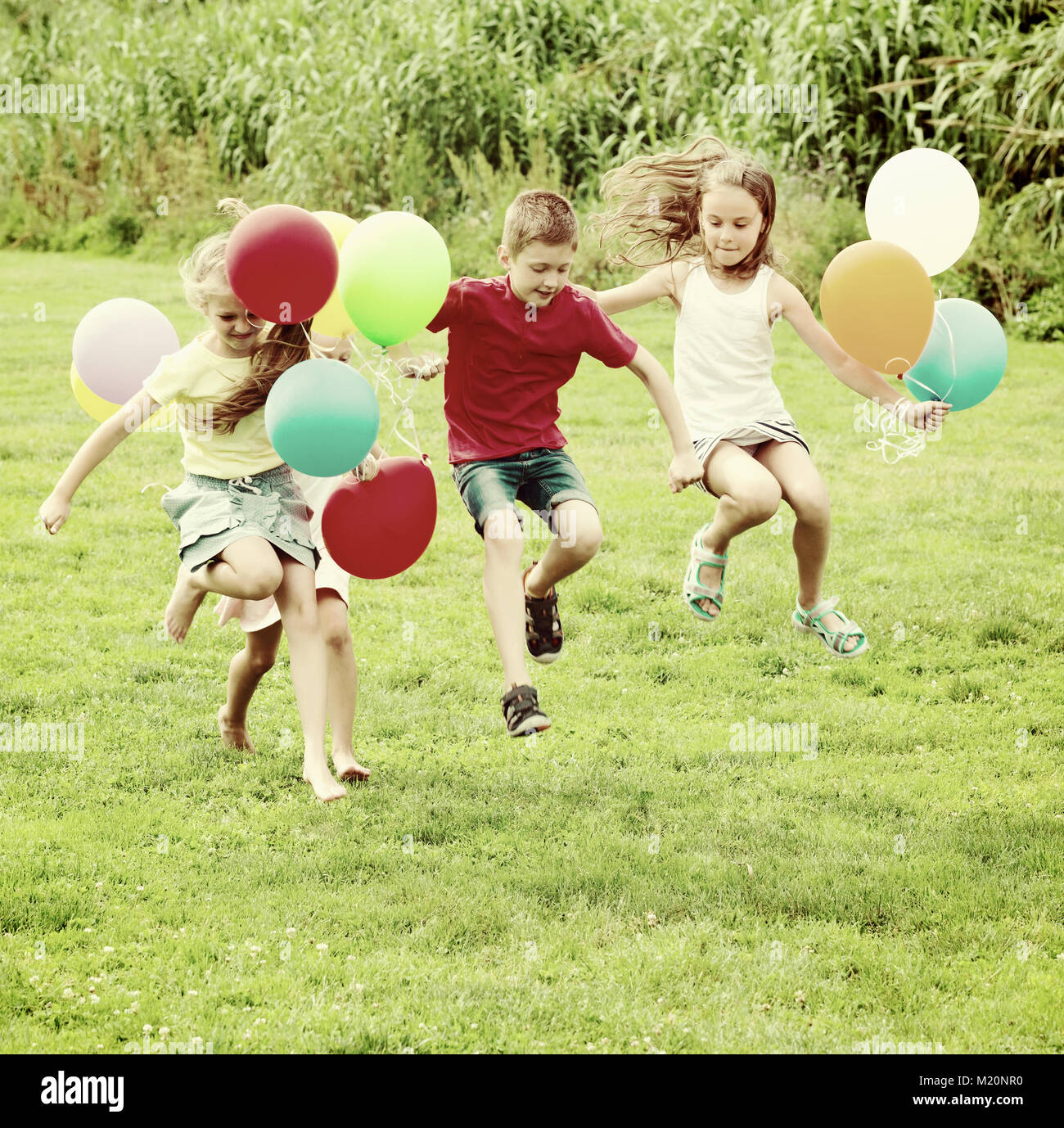 Children jumping and hop on green meadow in park with multicolored ...