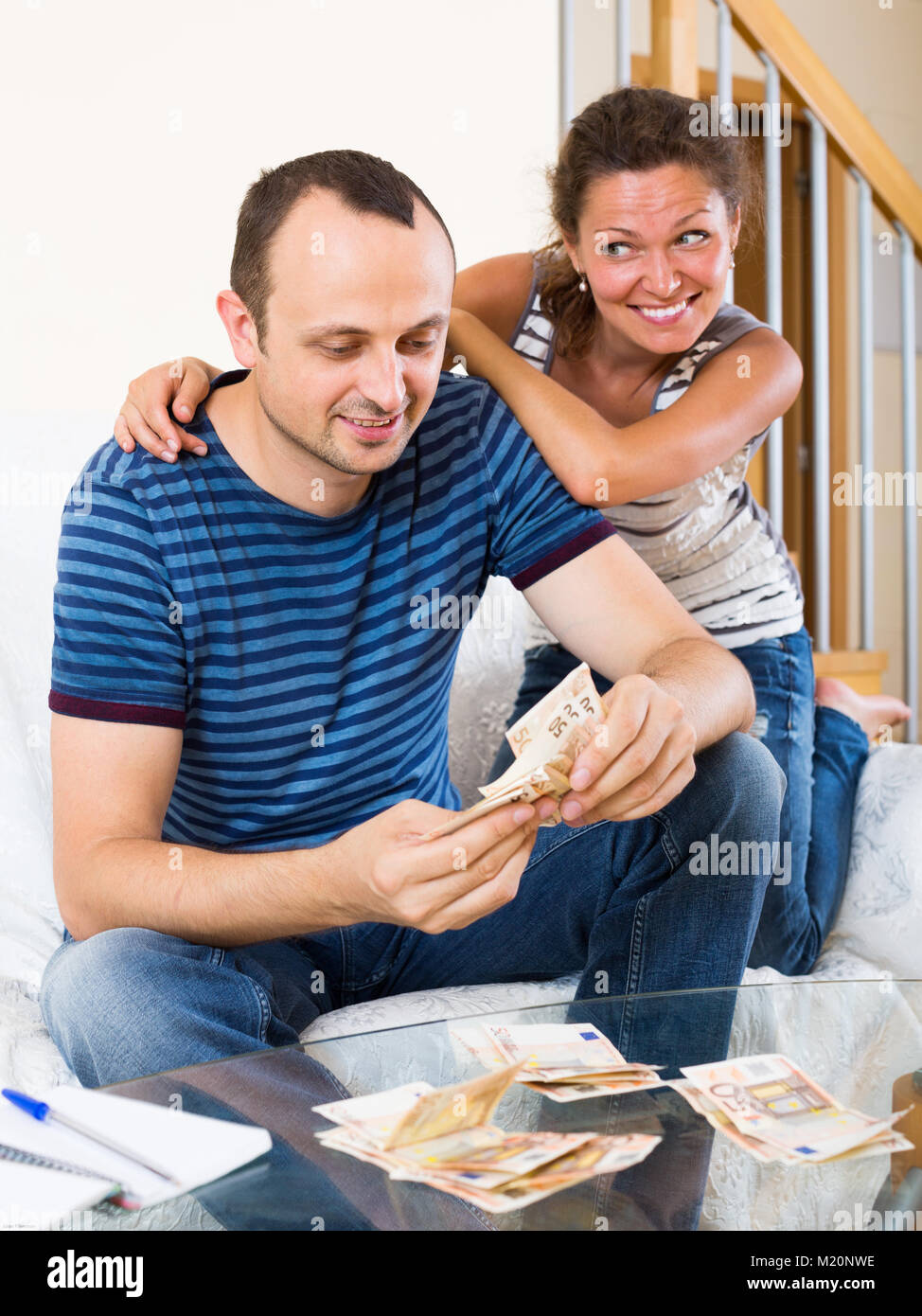 Sly wife asking smiling man money for shopping Stock Photo - Alamy