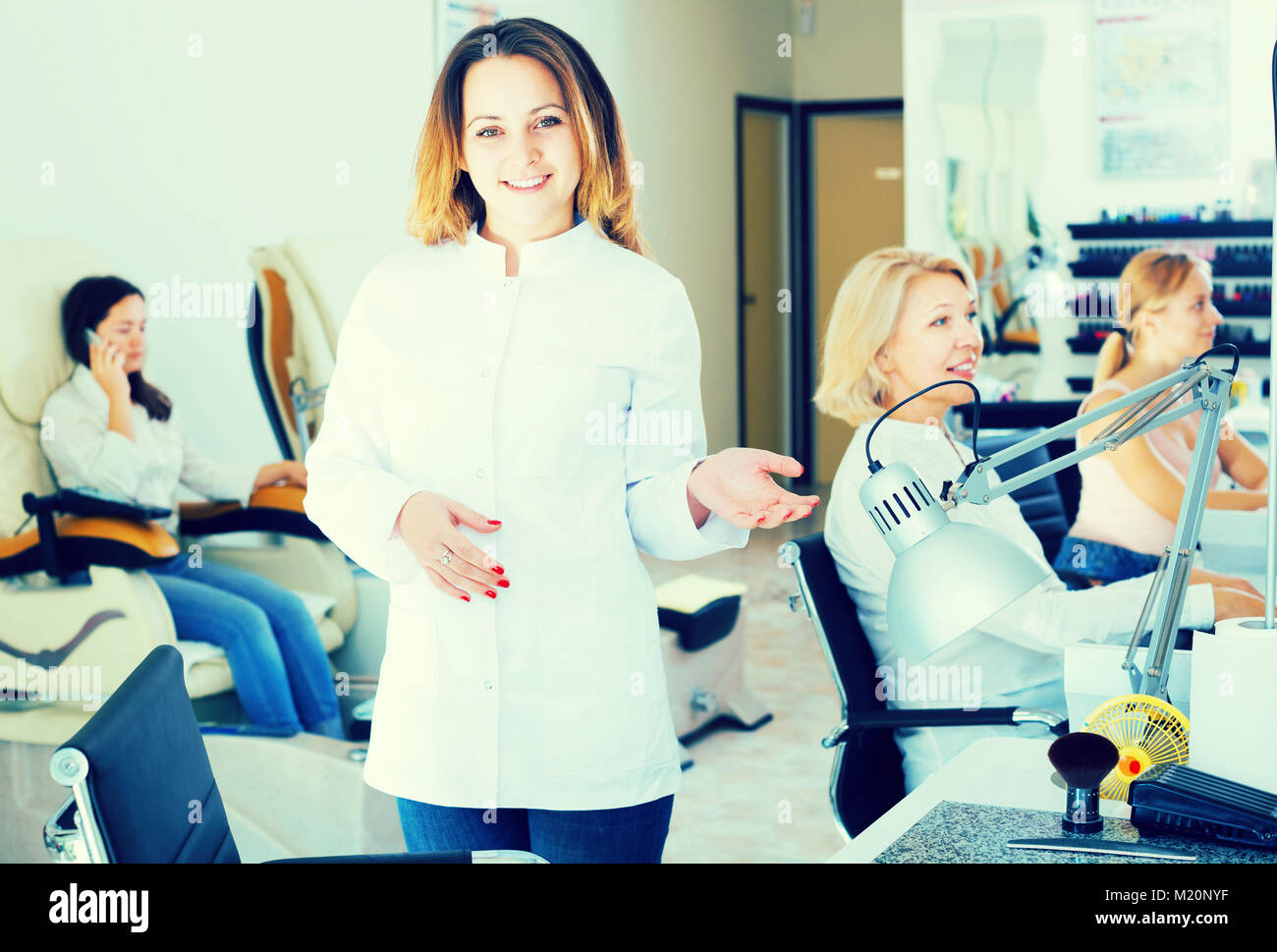 Pretty happy young woman doing nails displaying her workplace in nail ...