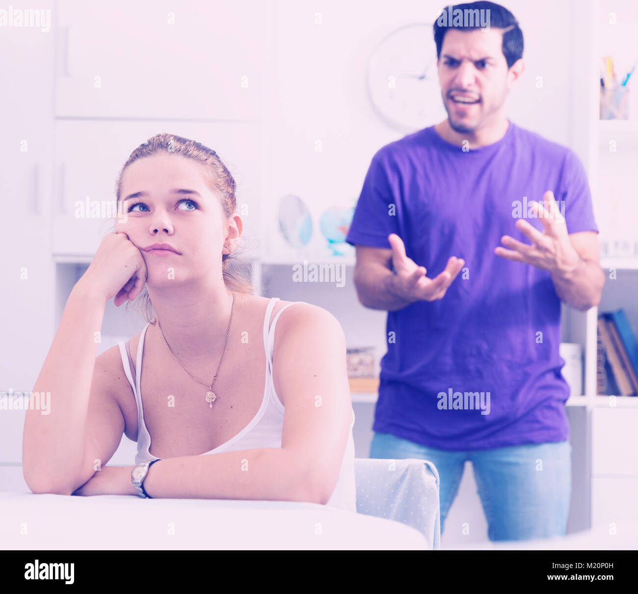 Frustrated girl sitting at home table on background with angry ...