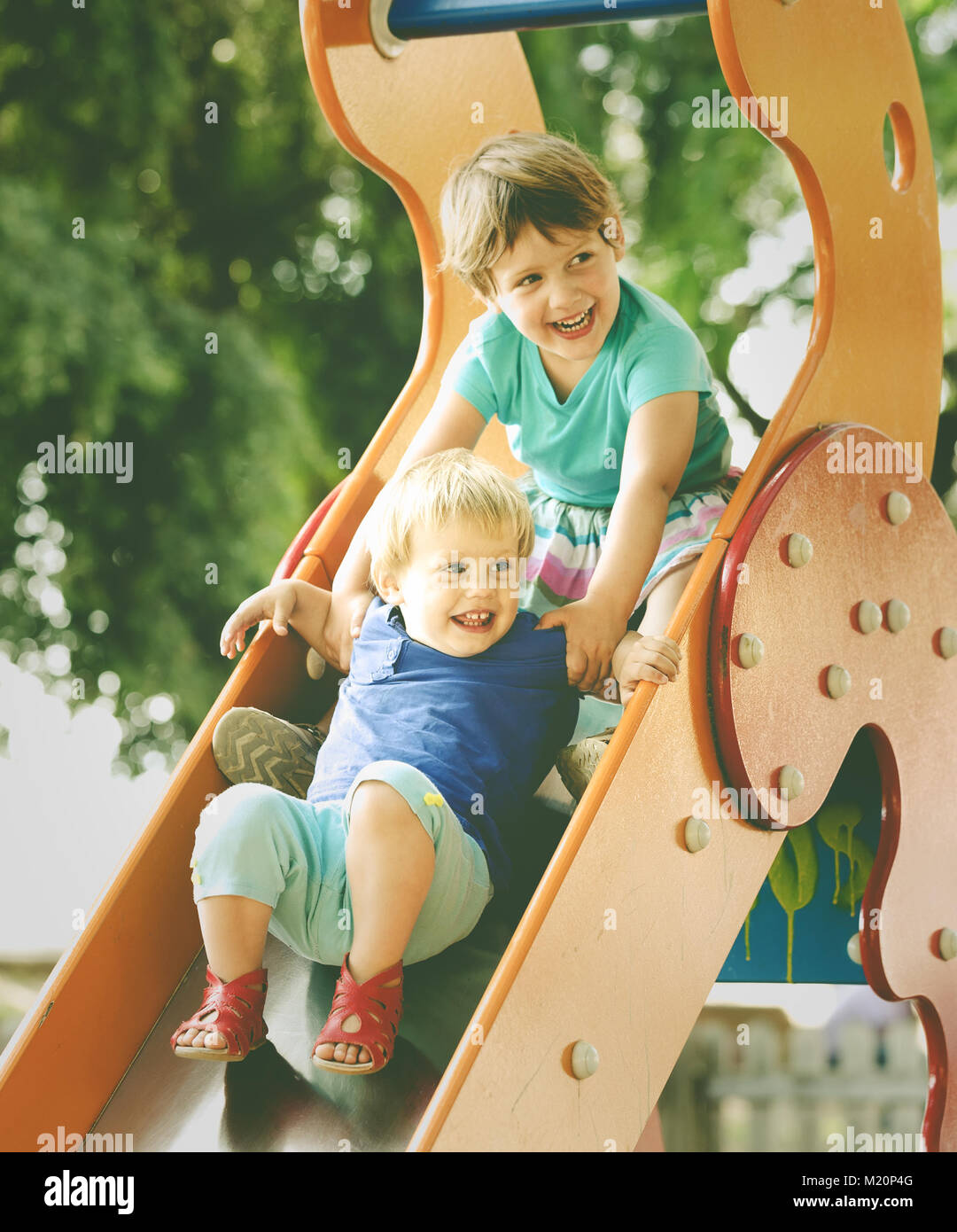 laughing children on slide at playground area in summer Stock Photo - Alamy