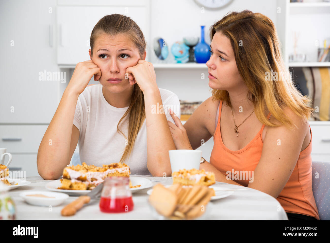 Portrait of female talking with sad girl friend at the kitchen Stock ...
