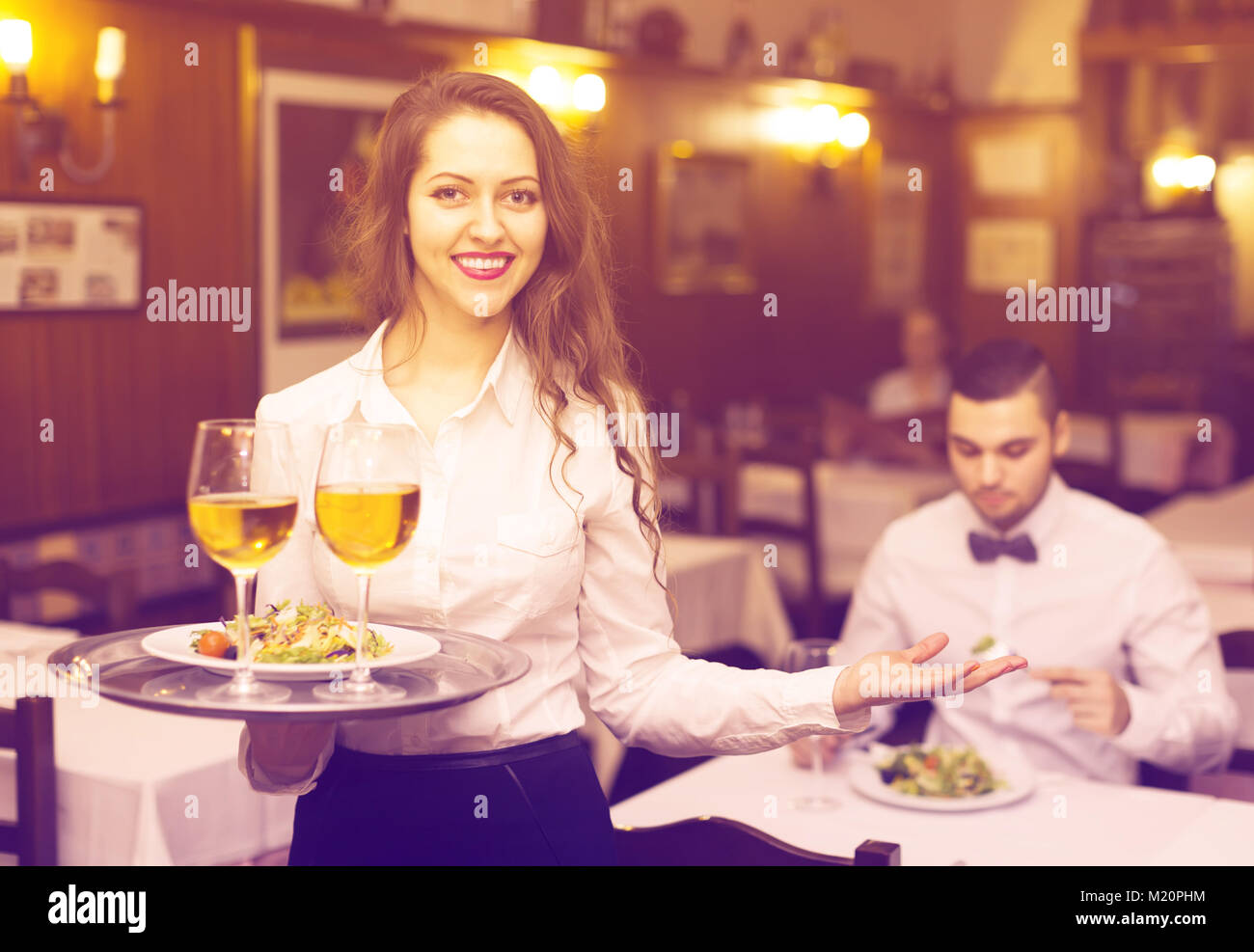 Charming young waitress with prepared meal at attendee table Stock ...