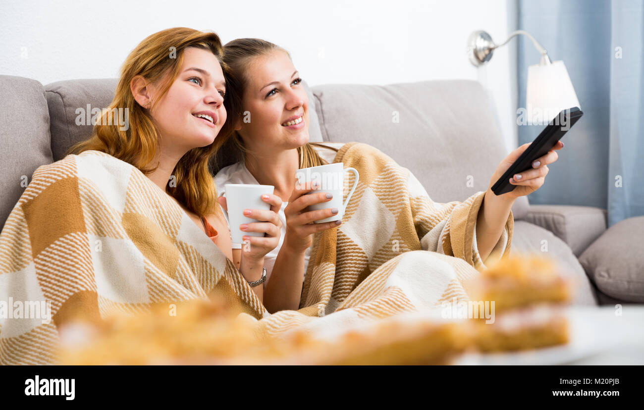 Two girlfriends are drinking tea in time watch TV at home Stock Photo ...
