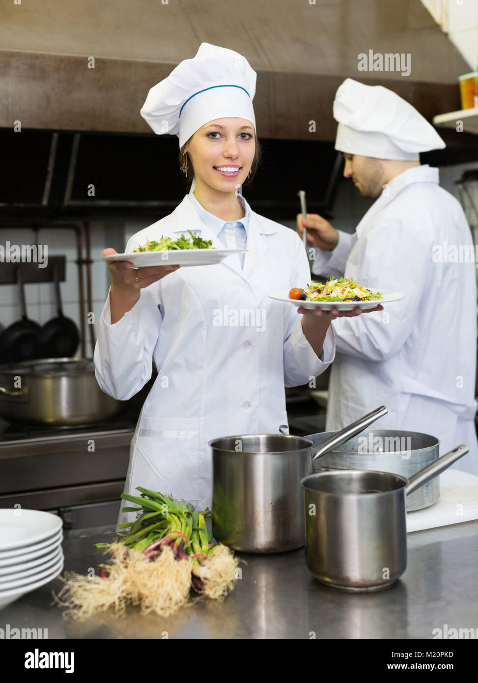 Positive shef and his assistant preparing meal in cafe Stock Photo - Alamy
