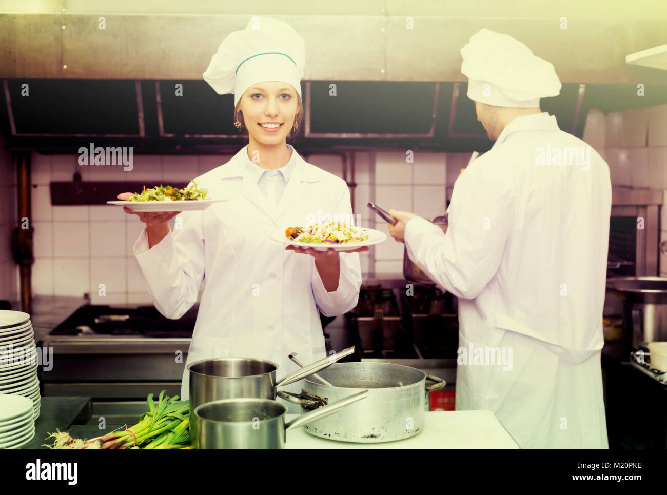 Two smiling professional cooks working at restaurant kitchen Stock ...