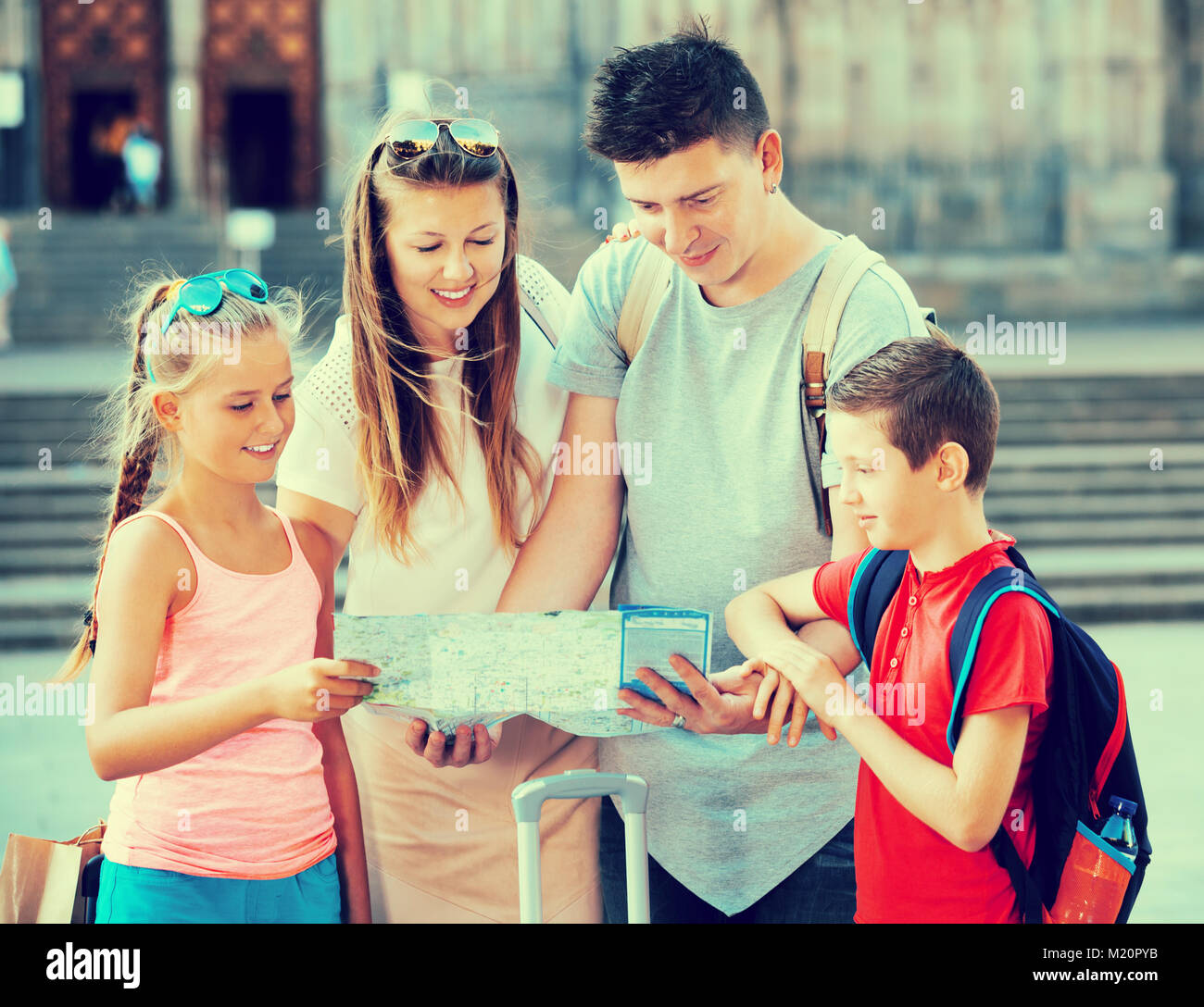 Positive family of tourists with two children looking for destination ...