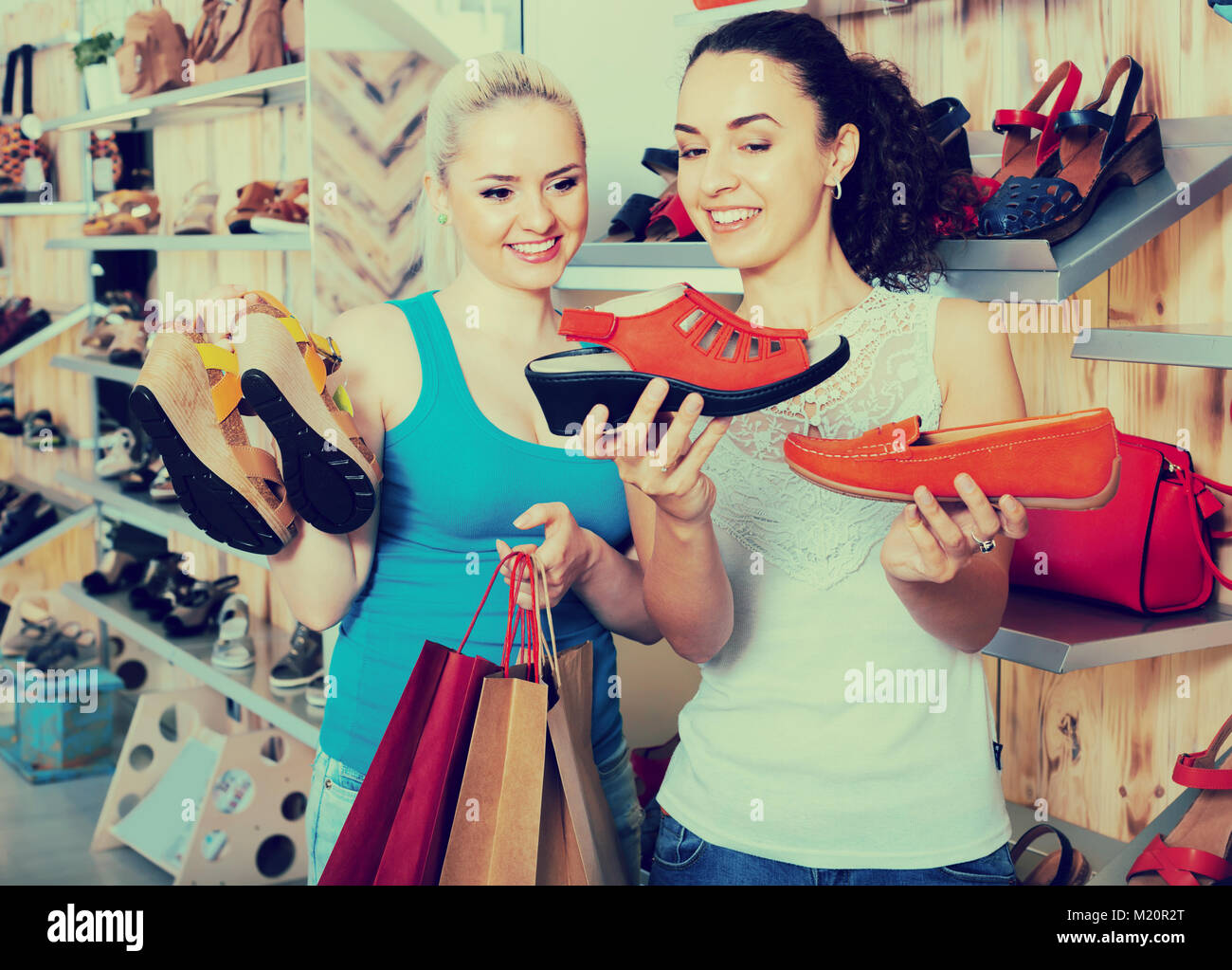 Two happy smiling young female friends choosing fashion shoes in the ...