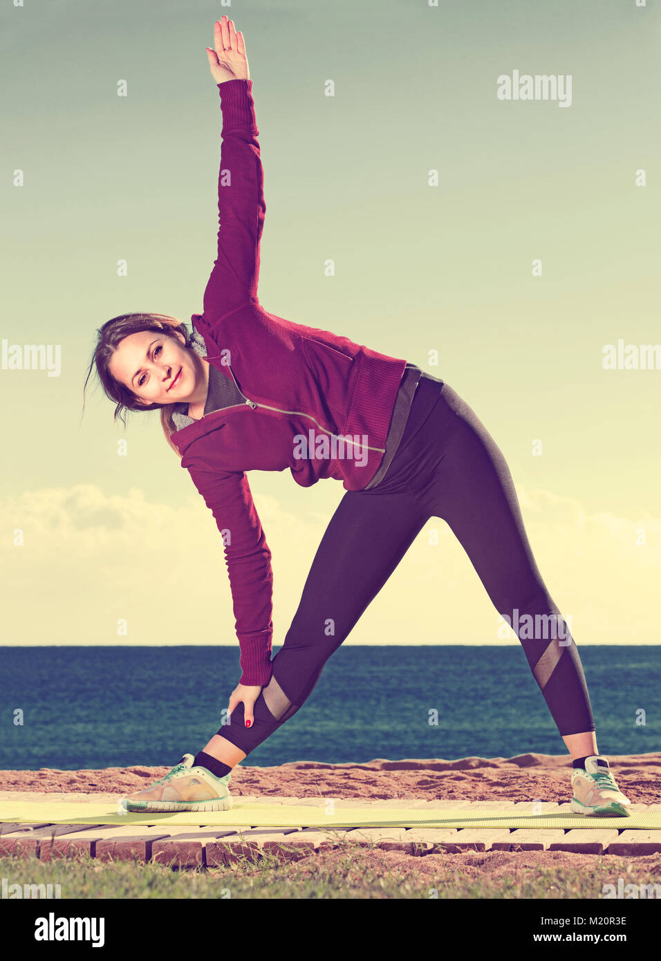 Young smiling cheerful woman doing youga at beach Stock Photo - Alamy