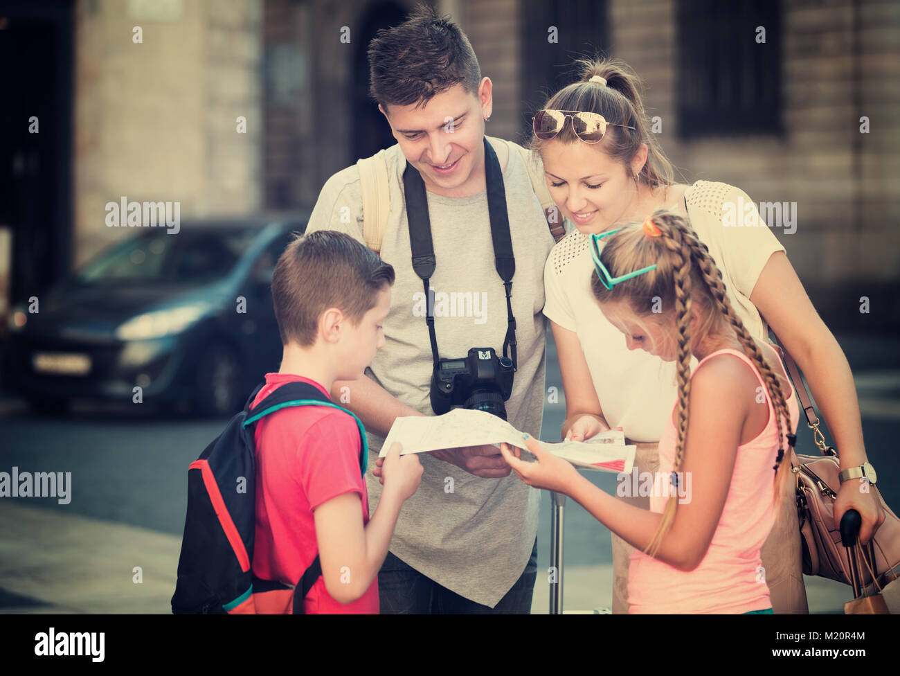 Young happy family of tourists with two kids looking for destination ...
