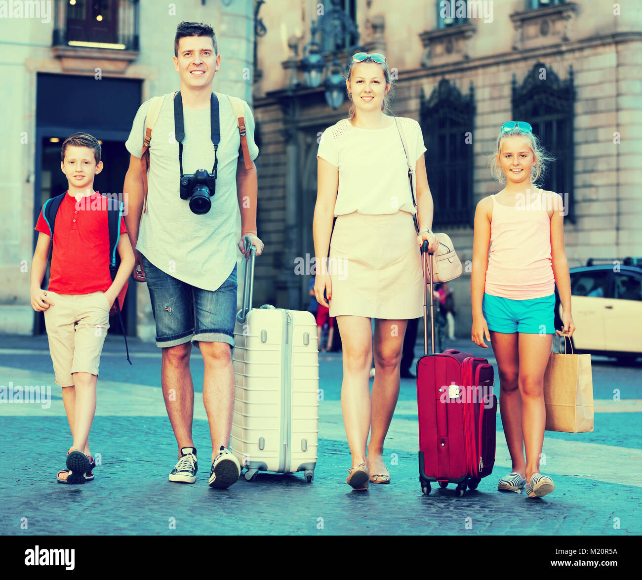 Young glad family of travelers with two children walking around city ...