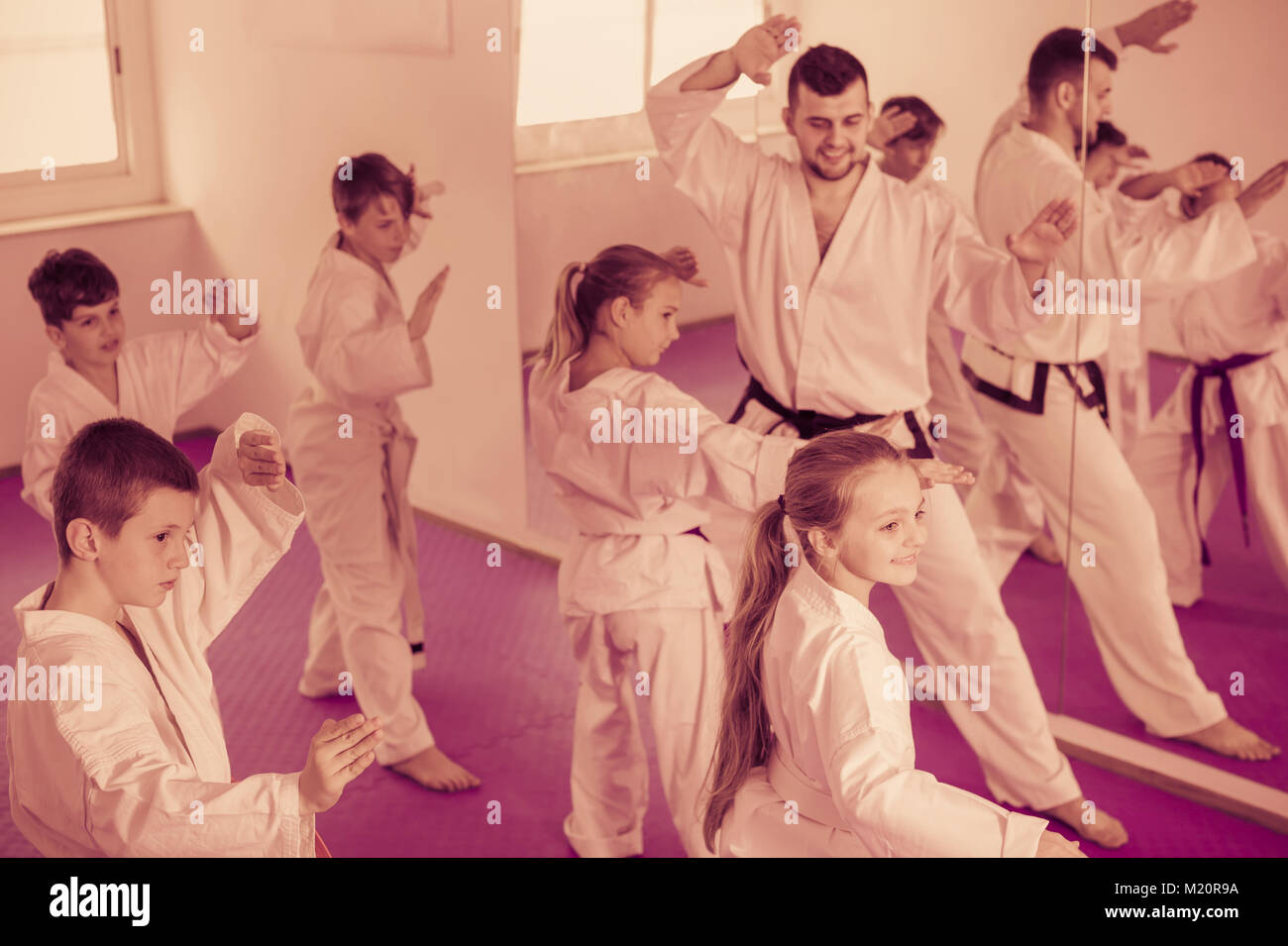 Smiling children attempting to master new moves during karate class ...