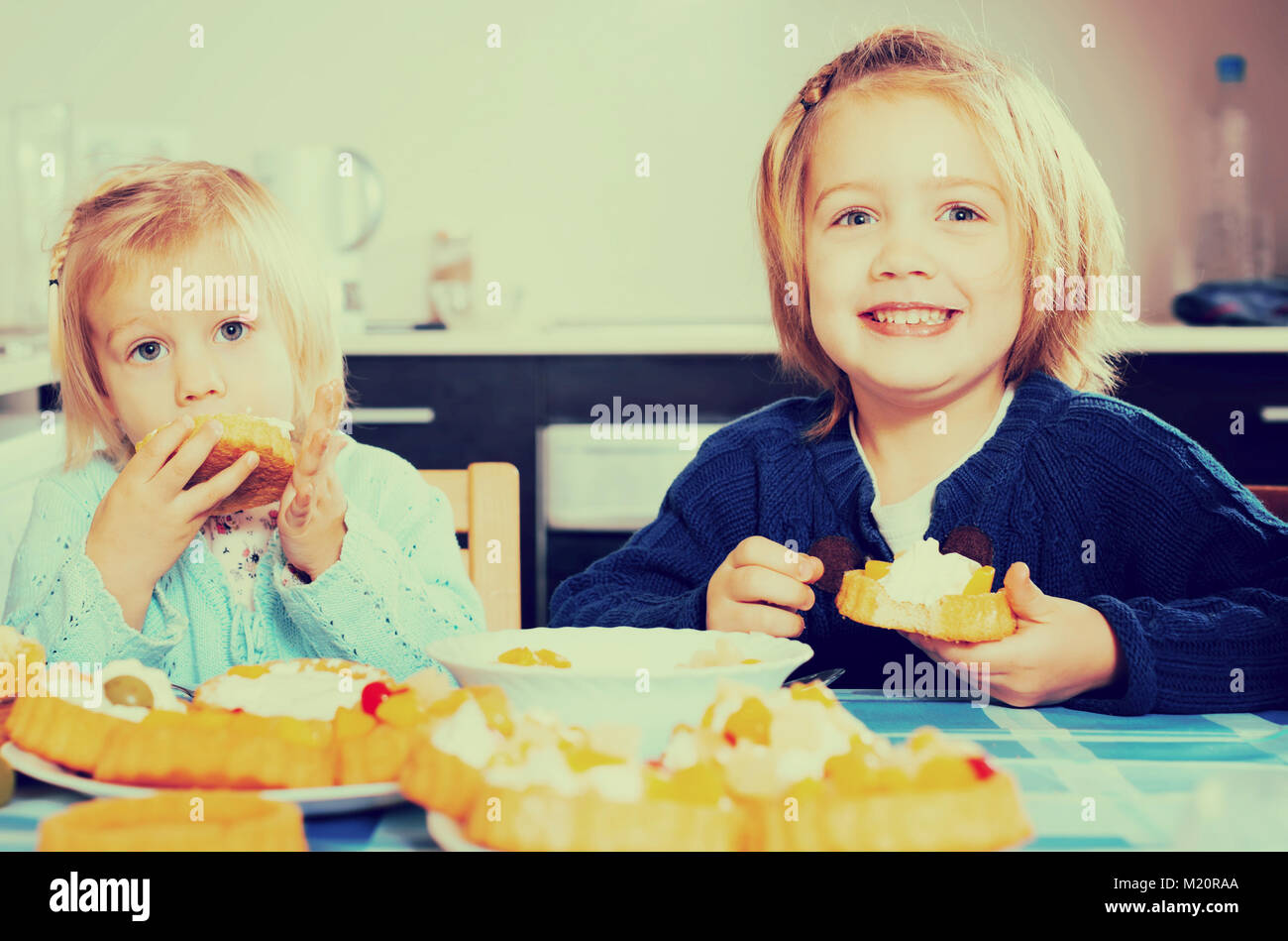 Smiling happy kids eating tasty pastry indoors in the kitchen Stock ...